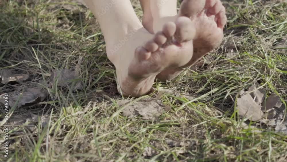 barefoot girl walks on spring grass, closeup seen legs, bright sunny ...