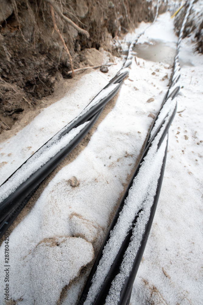 Laying a fiber optic and electricity cables in the frozen ground ...