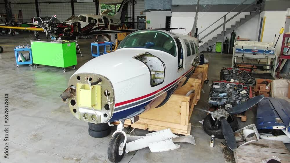 Dismantled twin engine propeller airplane in repair hangar, ascending ...