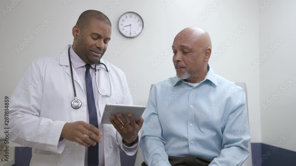 Doctor reviews chart with patient in doctor office, hospital exam room ...