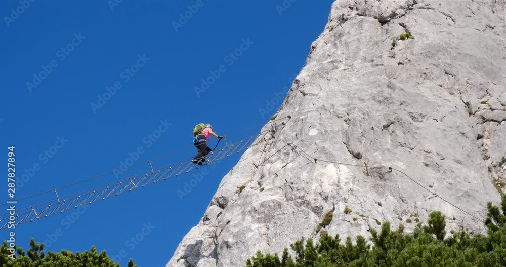 Epic shot of a woman advancing on a via ferrata diagonal ladder, high ...