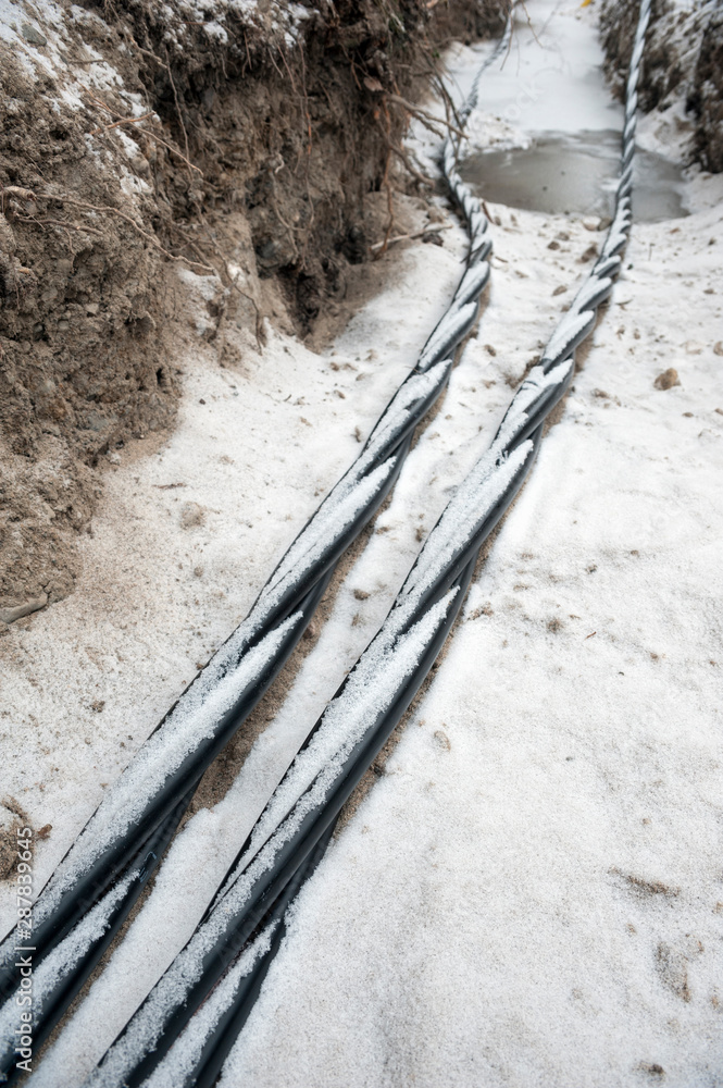 Laying a fiber optic and electricity cables in the frozen ground ...