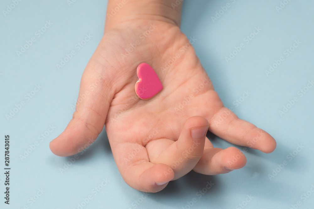child's hand on a blue background with a pink heart in the palm Stock ...