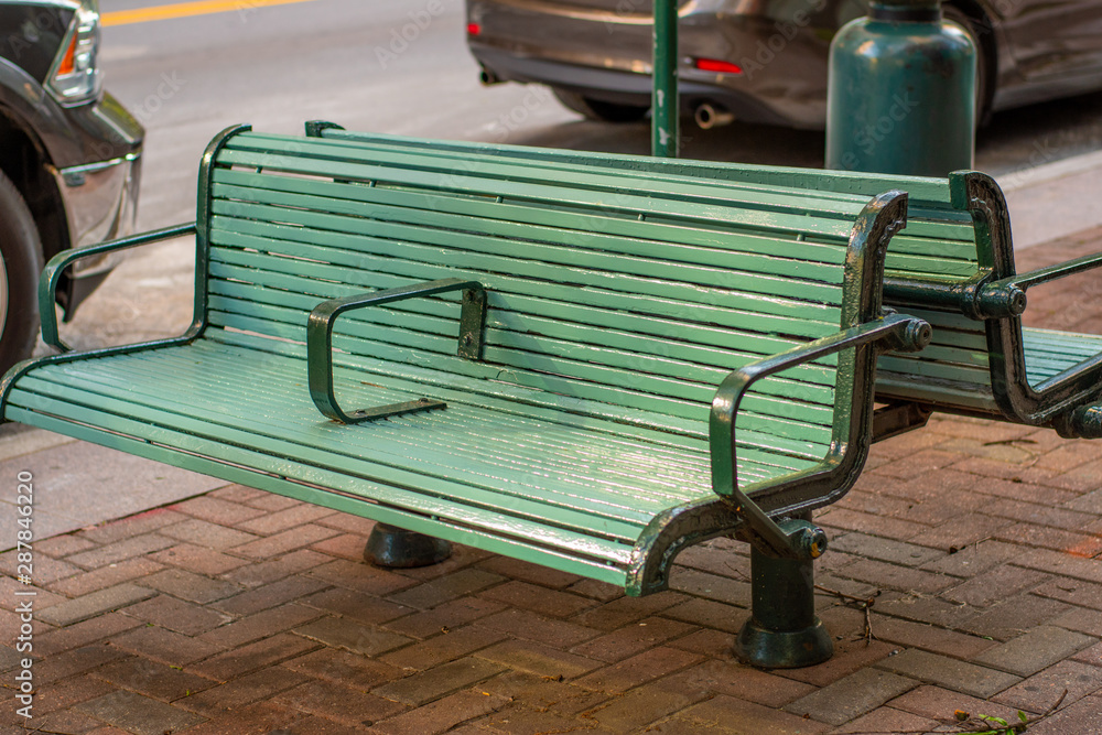 Green vintage city curbside wooden bench on uptown city street with ...