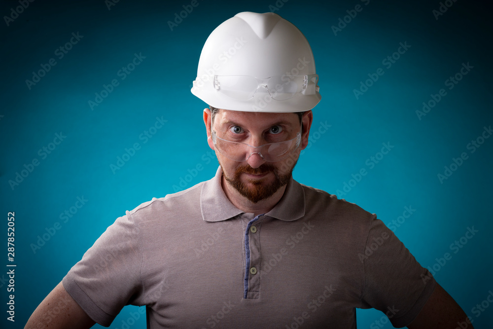 Construction worker with beard and white safety helmet looking stern ...