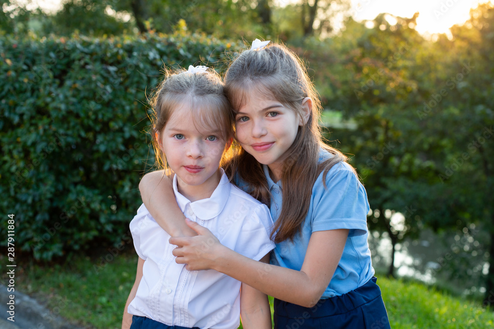 Foto Stock Two little girls friends in school uniform hug each other in ...