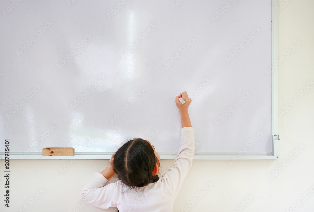 Little caucasian child girl writing something on whiteboard with a ...