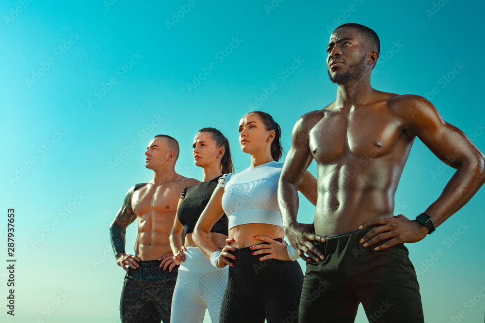 Group of four young sportsmens women and men, fit athletes are standing ...