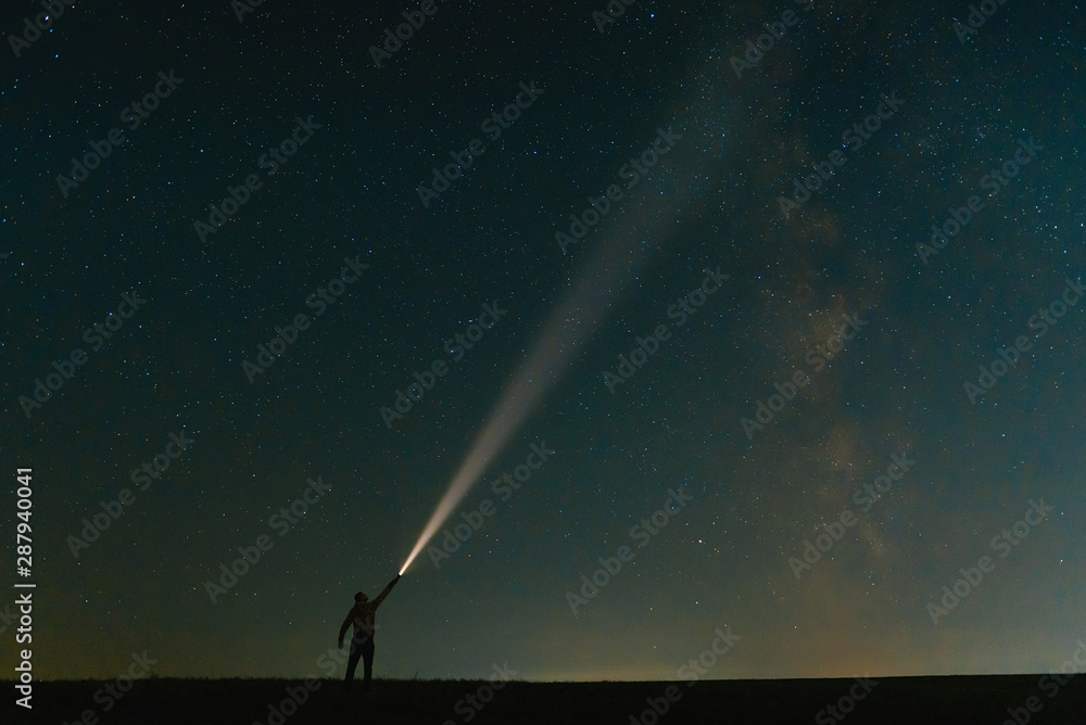 Back view of man with flashlight standing on green grassy field under ...