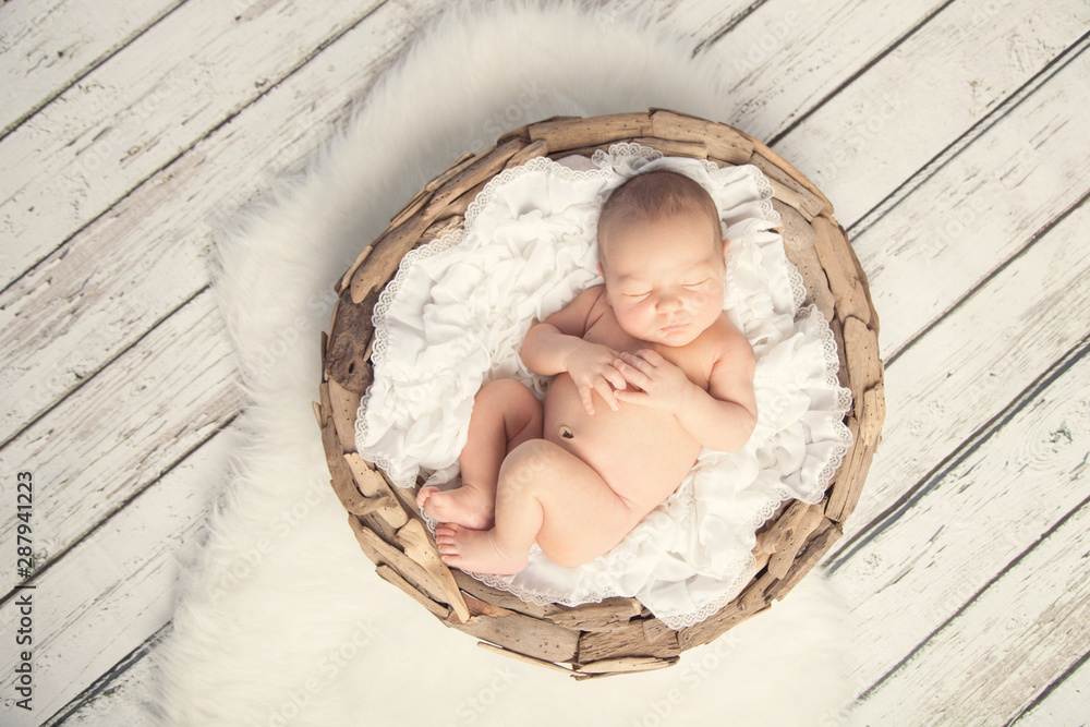 Newborn baby girl sleeping in basket on white wood floor and fur rug ...