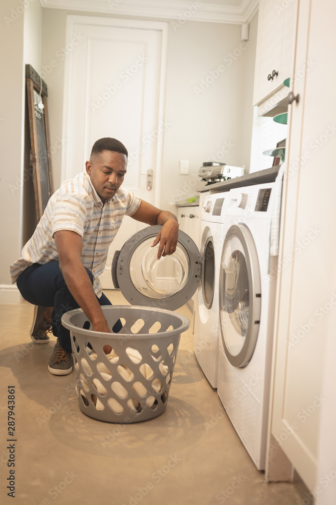 African American man washing clothes in washing machine Stock Photo ...