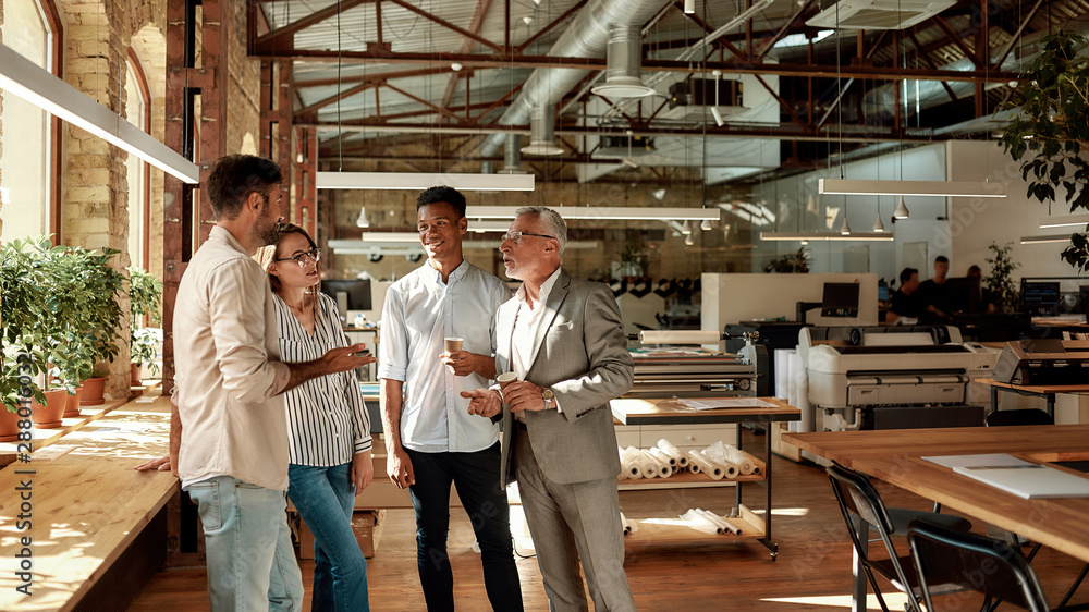 Foto de Discussing new project. Four colleagues holding coffee cups and ...