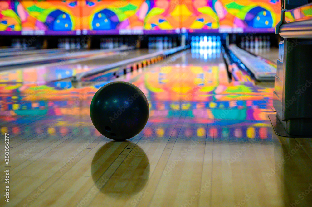 Bowling ball in focus with blurred view down bowling alley with gutter ...