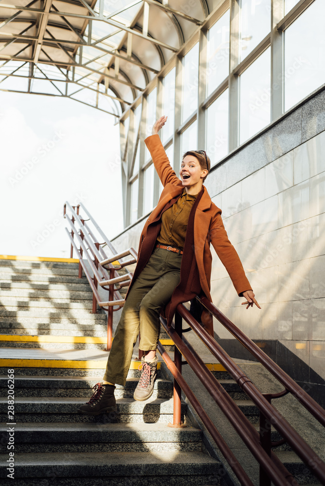 Excited woman sliding down from railing Stock Photo | Adobe Stock