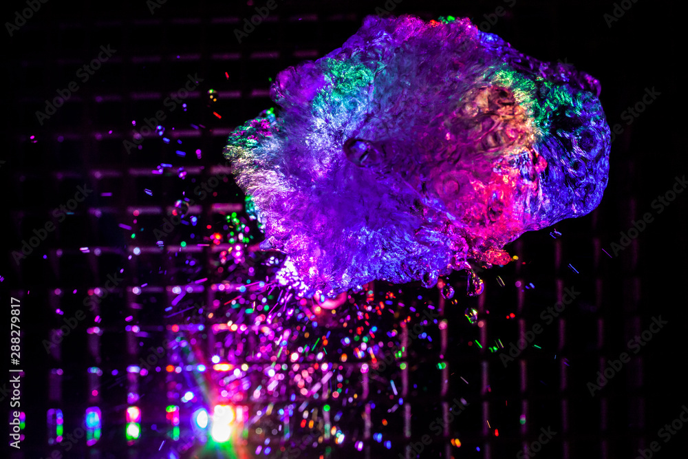Abstract background of water splashes in multi-colored lighting. The ...