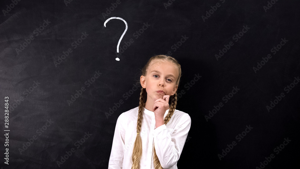 Child thinking about hometask solution, question mark on blackboard ...