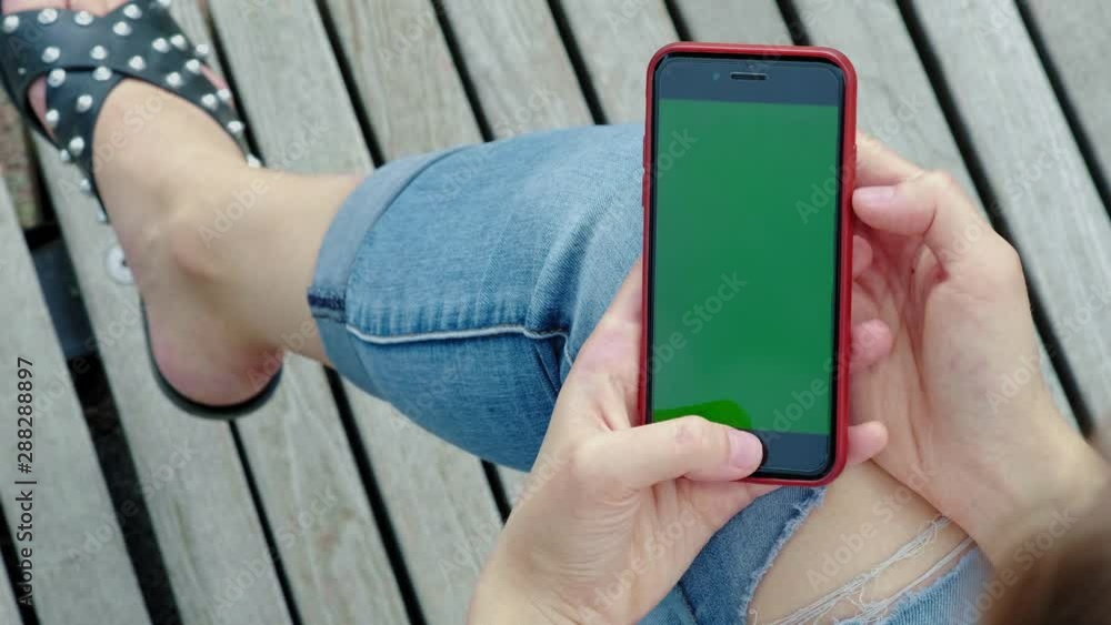 Beautiful girl holding black smartphone in the hands of a green screen ...