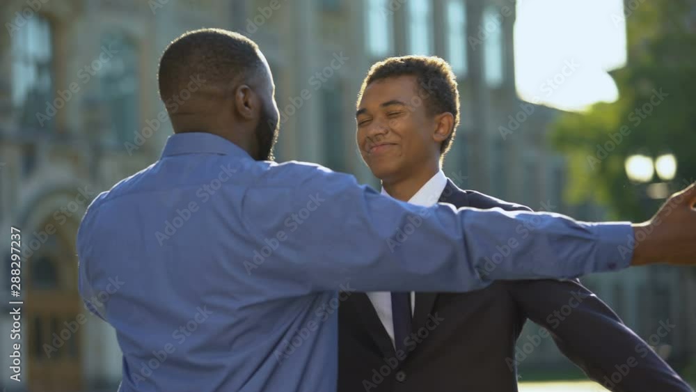 Vidéo Stock Glad parent hugging young son in suit outdoors university ...