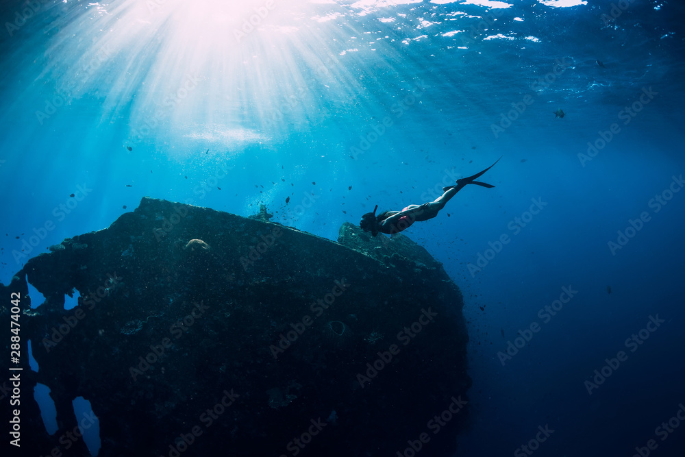 Freediver girl in pink swimwear with fins swimming underwater at wreck ...