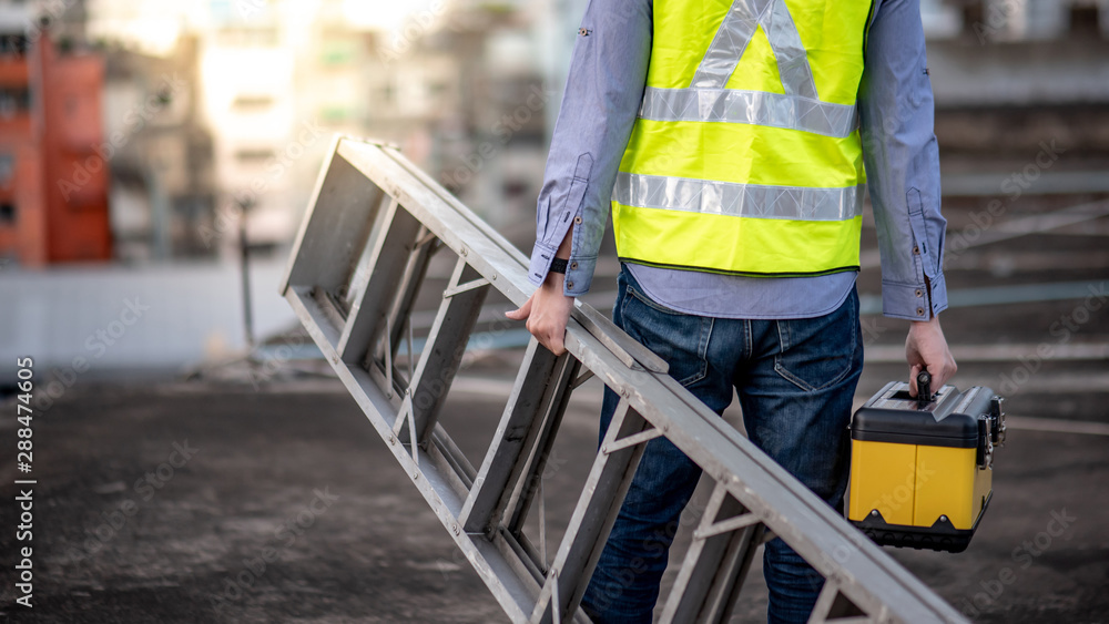 Maintenance worker man with safety helmet and green vest carrying ...