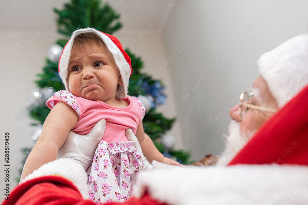 Little baby scared of Santa Claus. Crying scared at the big white beard ...
