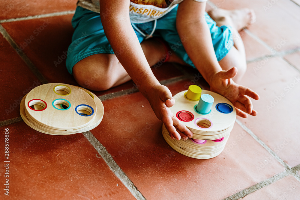Child having fun with an educational wooden game, to fit cylinders into ...