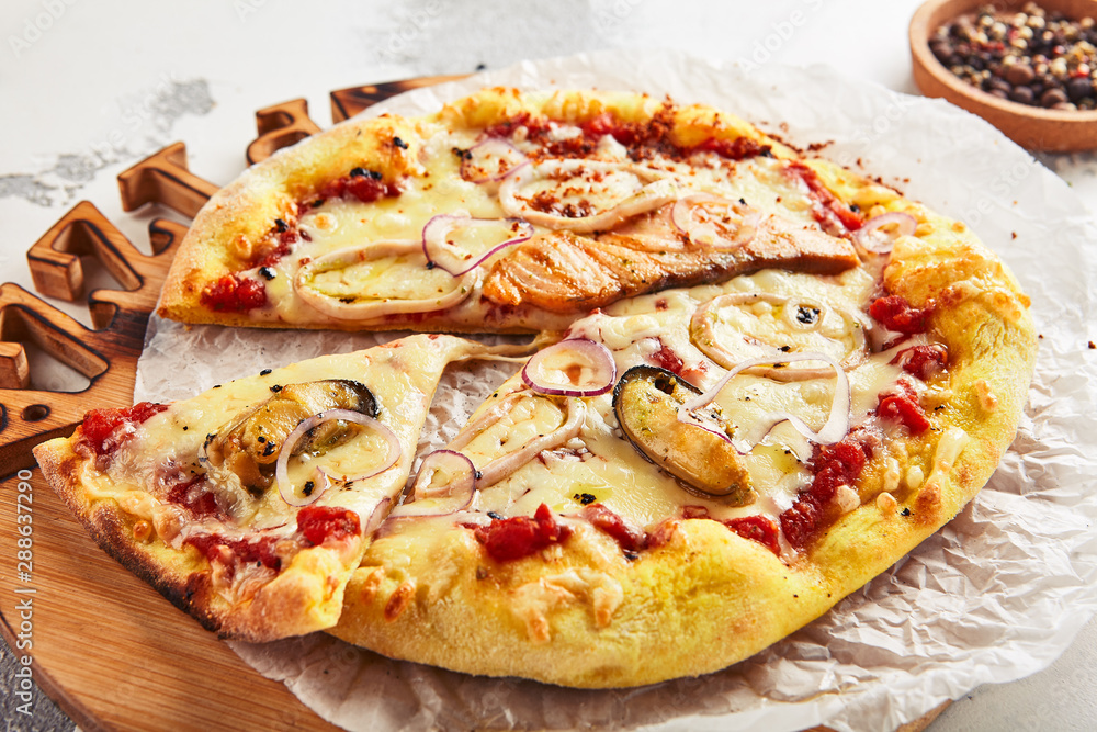 Foto de Hot seafood pizza with squid, mussels and fish fillet on wooden ...