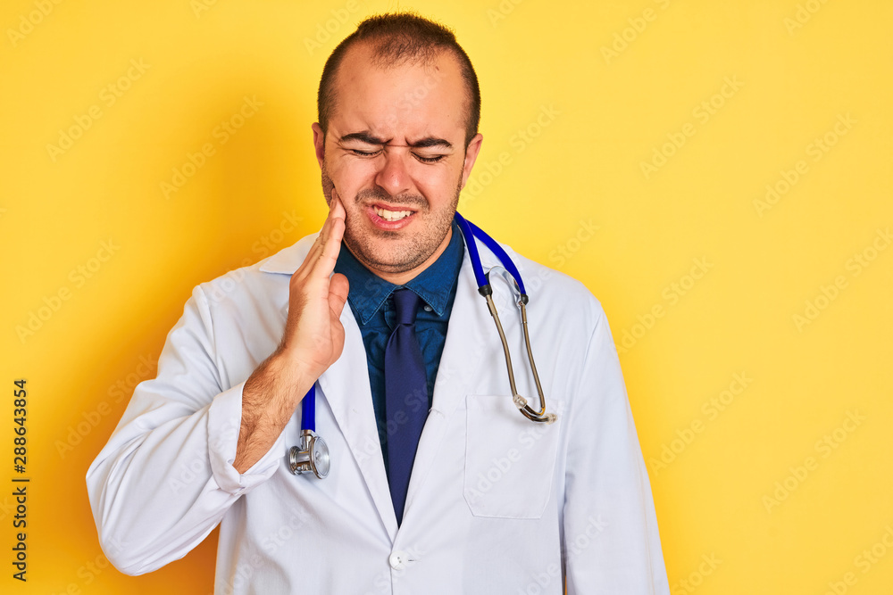 Young doctor man wearing coat and stethoscope standing over isolated ...