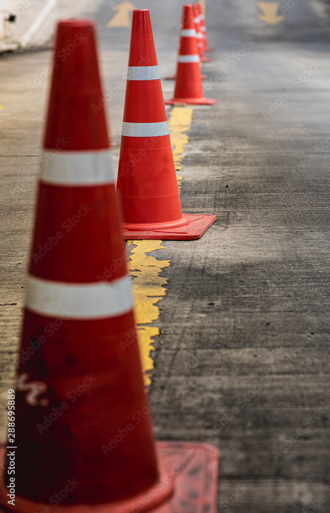 Orange traffic cones lined up on yellow lines on a small road guiding ...