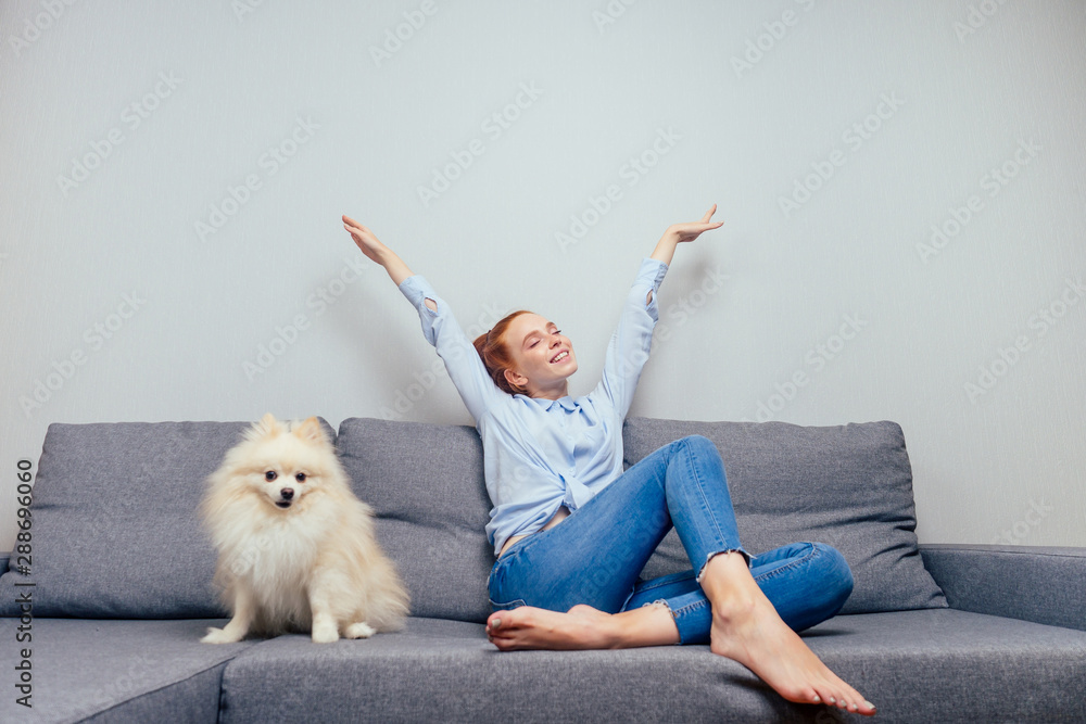 happy, redhaired ginger woman in shirt and jeans satting with her white ...
