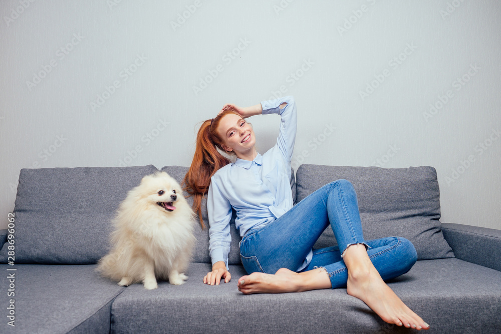 happy, redhaired ginger woman in shirt and jeans satting with her white ...