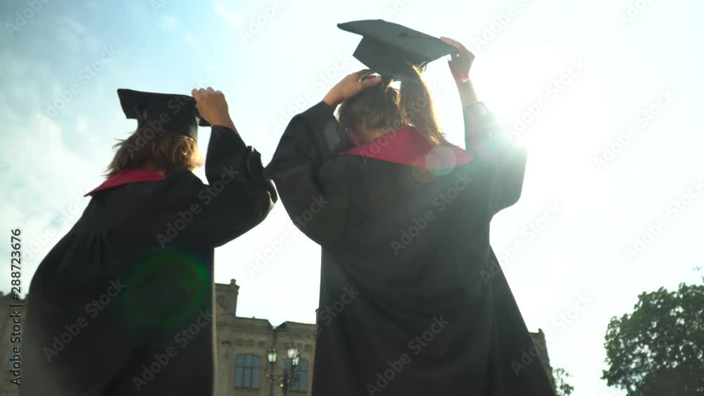 Back view two students in mantles celebrating their graduation in front ...