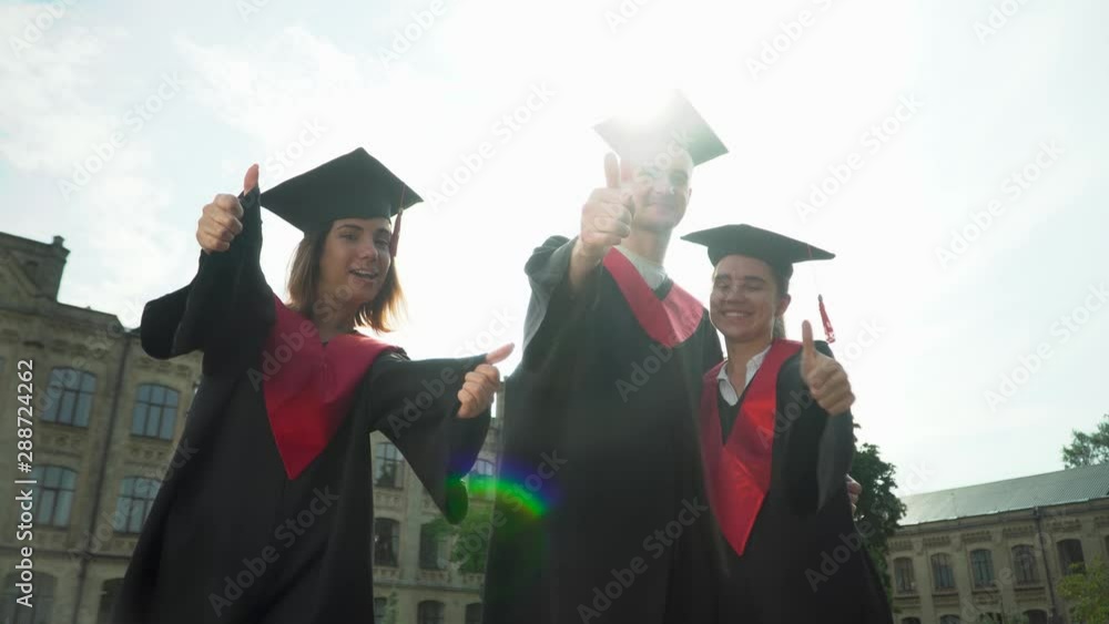 Three students celebrating their graduation in front of university ...