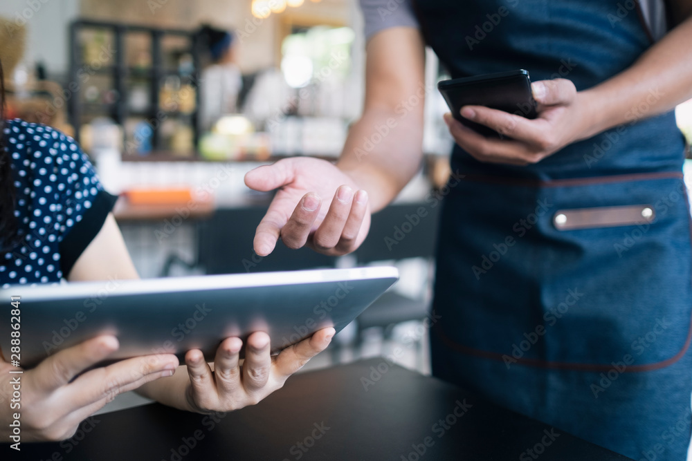 Young waiter using a digital tablet to show the menu to a customer ...