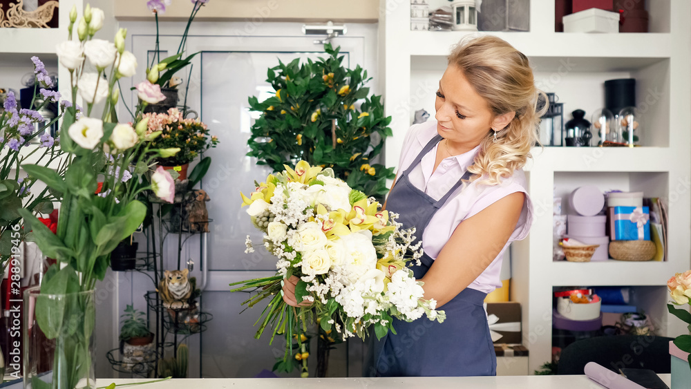 Professional florist woman creates lovely flower bouquet with roses ...