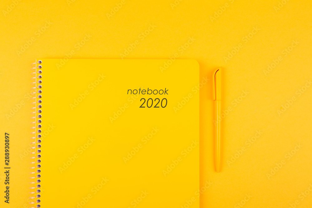 Notebook on a yellow background, top view, plans for 2020, year results ...