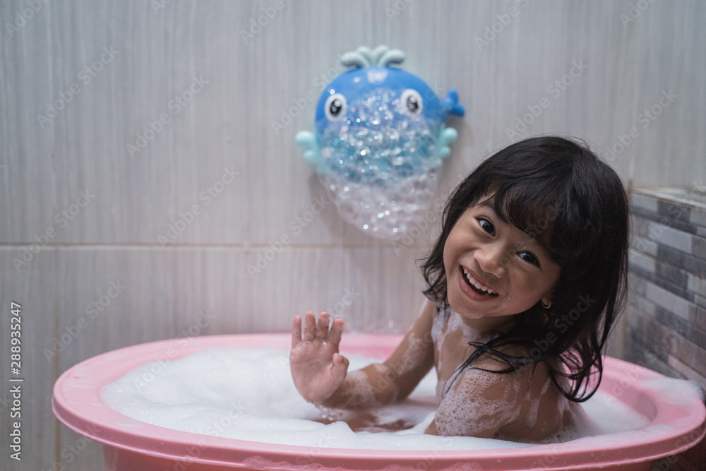 Asian little girl smilling when take a bath with foam in the bathroom ...