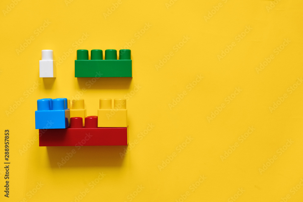 Colorful plastic building blocks flat lay. Yellow background. Child ...