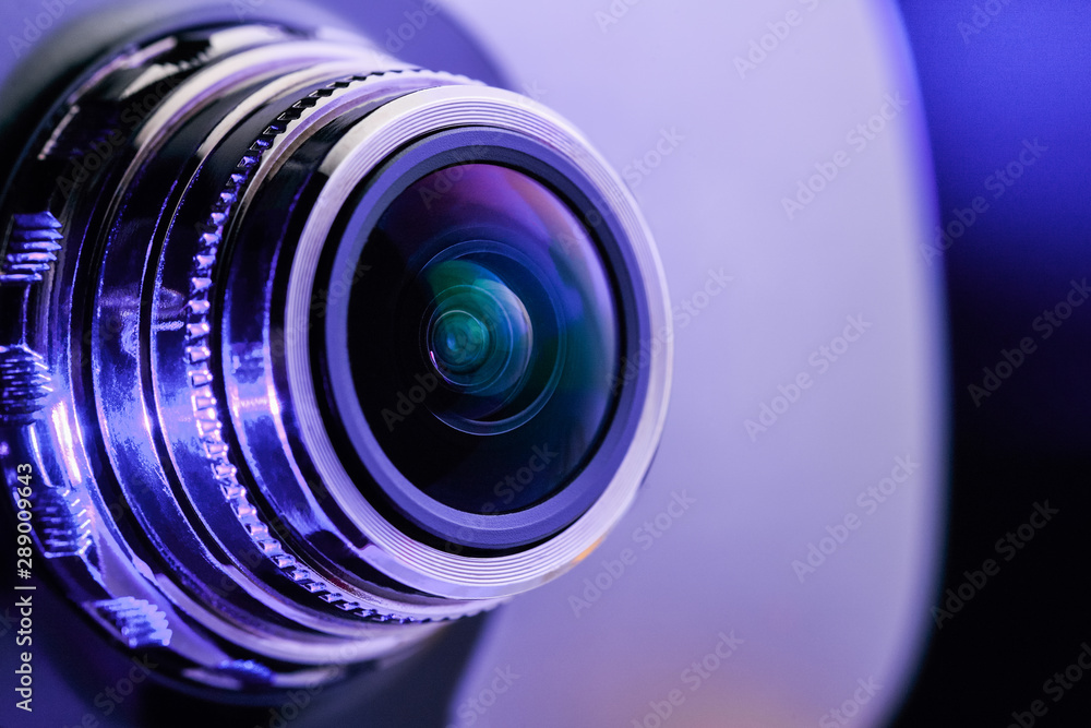 Camera lens with blue light. Side view of the lens of camera on blue ...