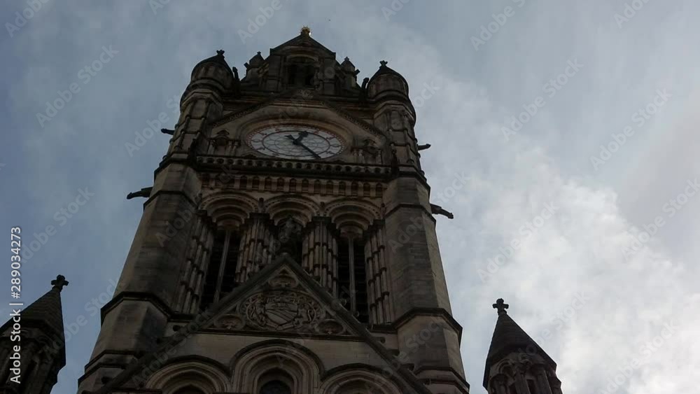 Manchester town hall clock face tower, static shot a clouds pass behind ...