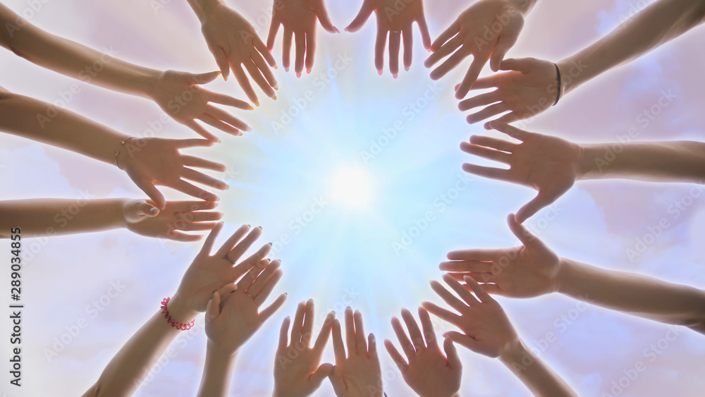 A group of young people make a circle out of their hands. Diverse ...