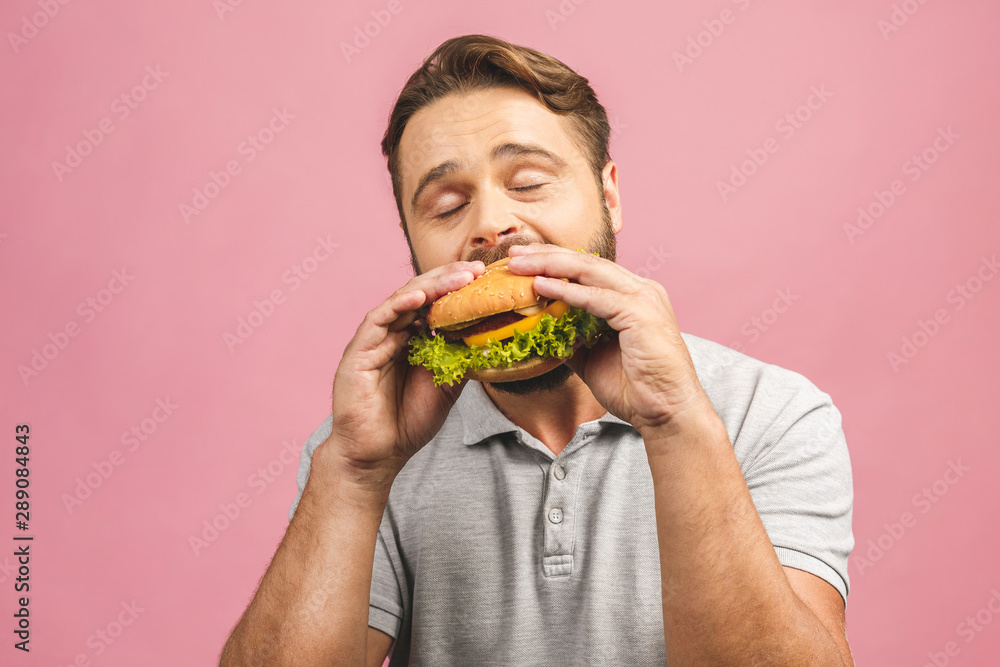 Young man holding a piece of hamburger. Bearded gyu eats fast food ...