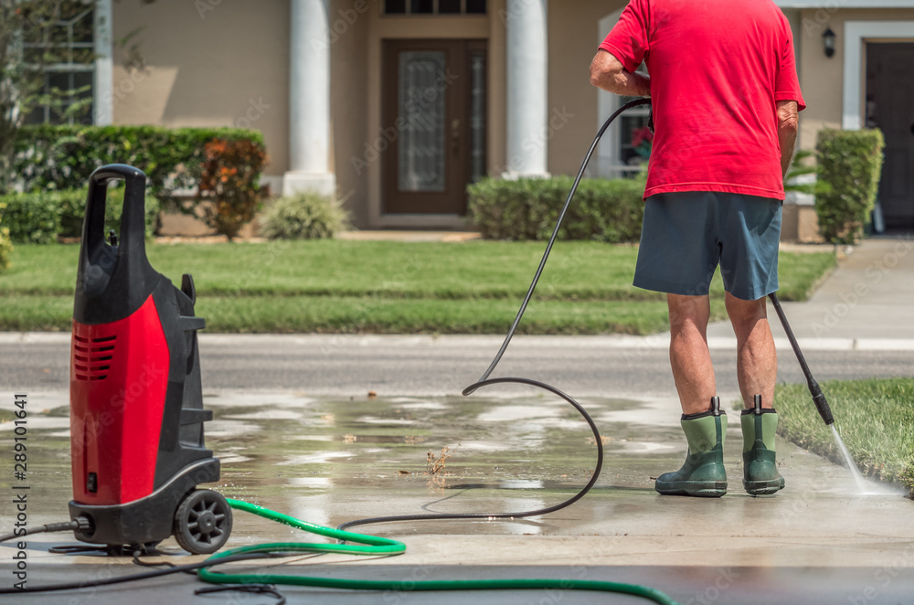 Man using electric powered pressure washer to power wash residential ...