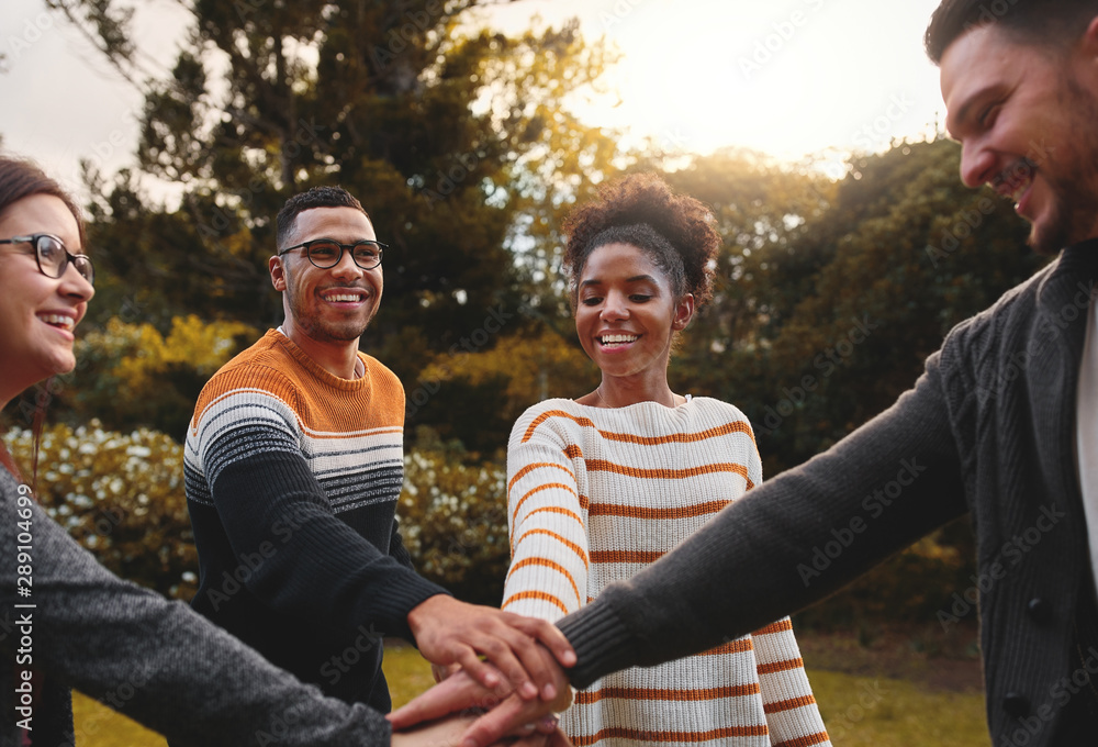 Group of smiling diverse friends stacking hands to express unity and ...