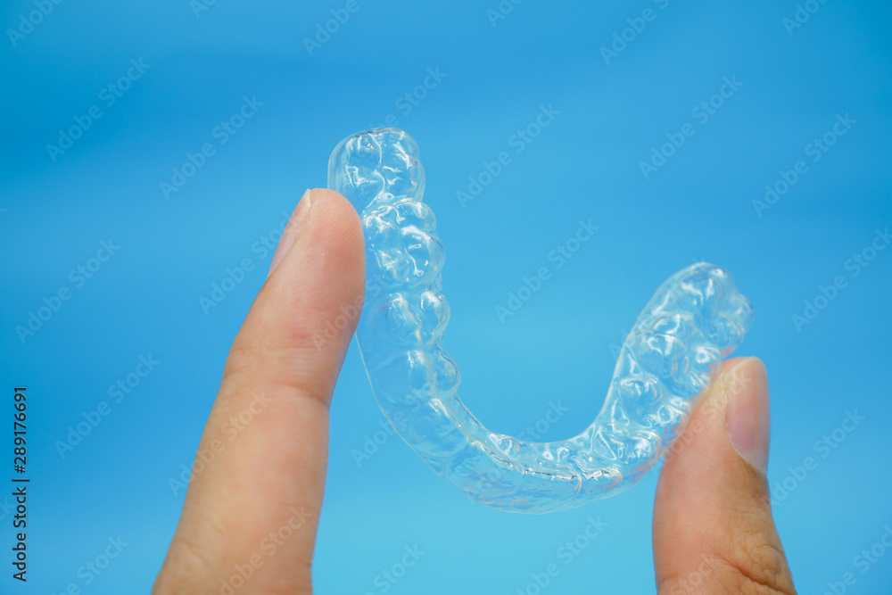 hand holding clear plastic retainer teeth that isolated on blue sky ...