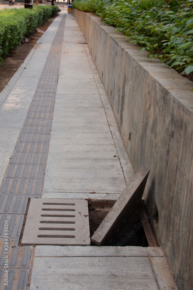Sewage drain with open concret grate on the sidewalk. Sewer manhole ...