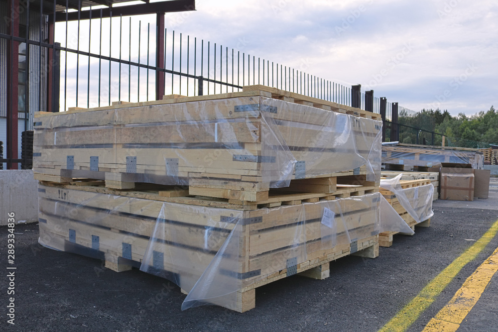 Lattice wooden box packed in polyethylene from rain and moisture stands ...
