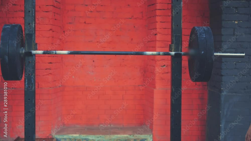The rider stands with a very heavy bar on his shoulders. He is at the ...