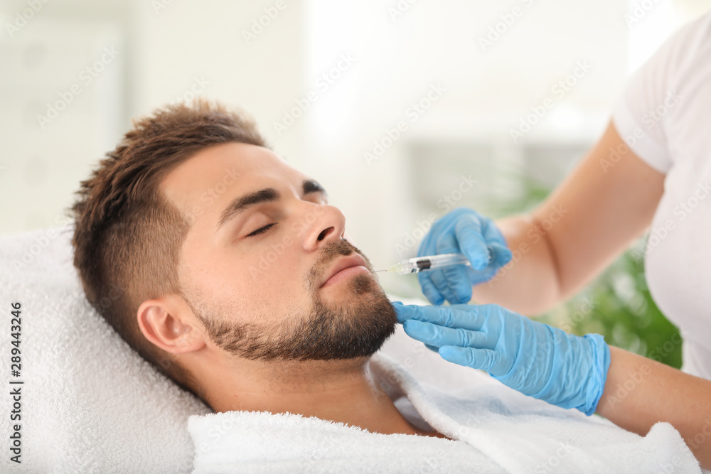 Handsome man receiving filler injection in beauty salon Stock Photo ...