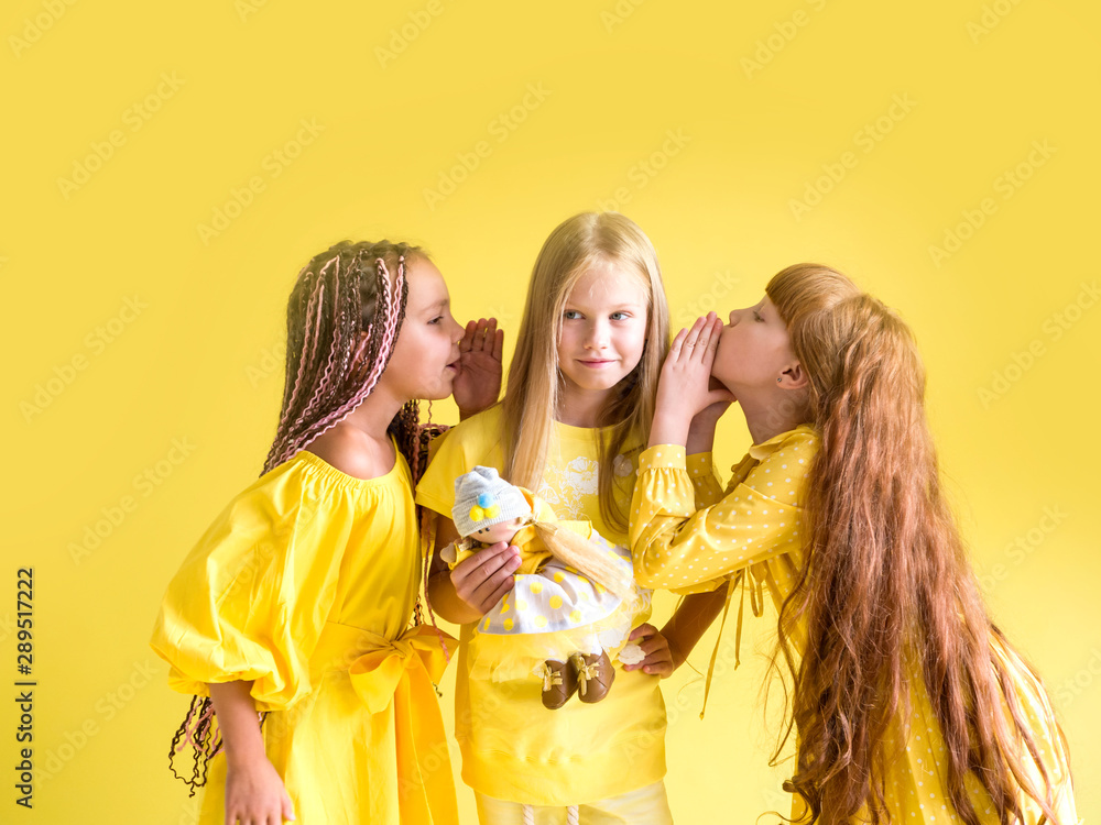 Group of beautiful girls in yellow clothes with long hair whisper in ...